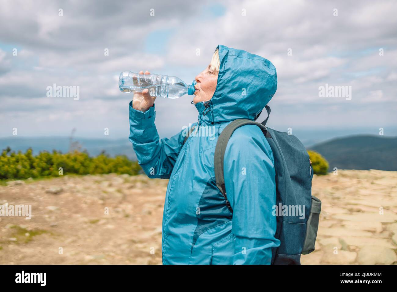 Elderly 50s woman drinking water from bottle in the mountains Stock ...