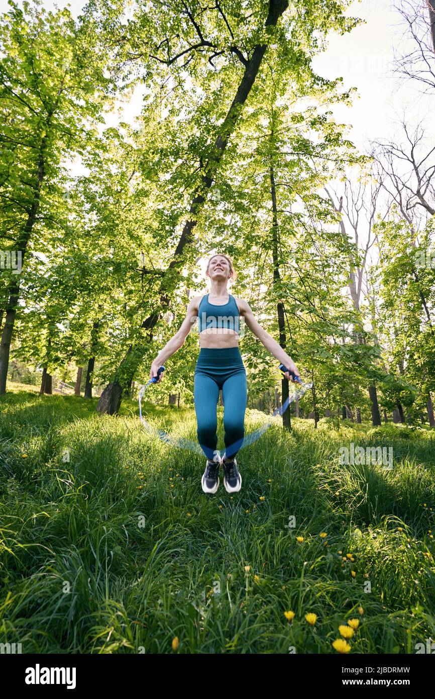 Happy athletic woman kipping during training in nature Stock Photo - Alamy