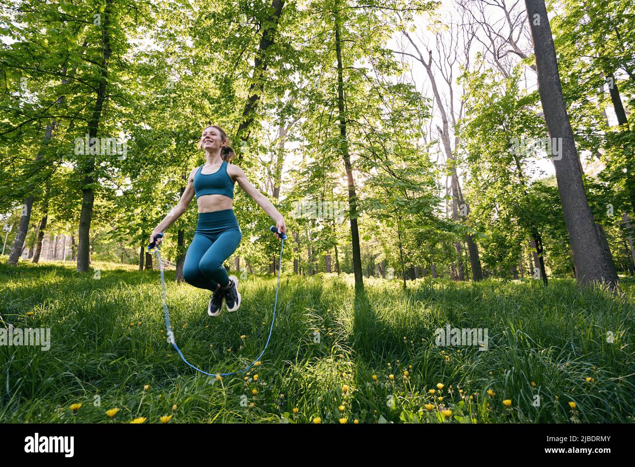 Joyful woman using jumping rope in nature Stock Photo - Alamy