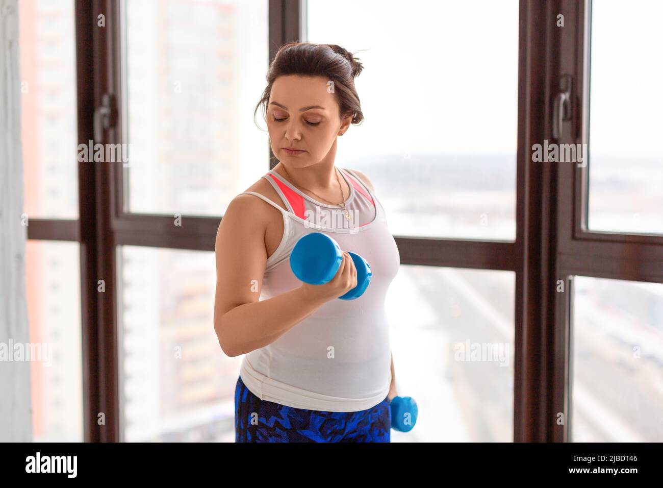 Portrait of a middle aged woman during home workout with dumbbells ...