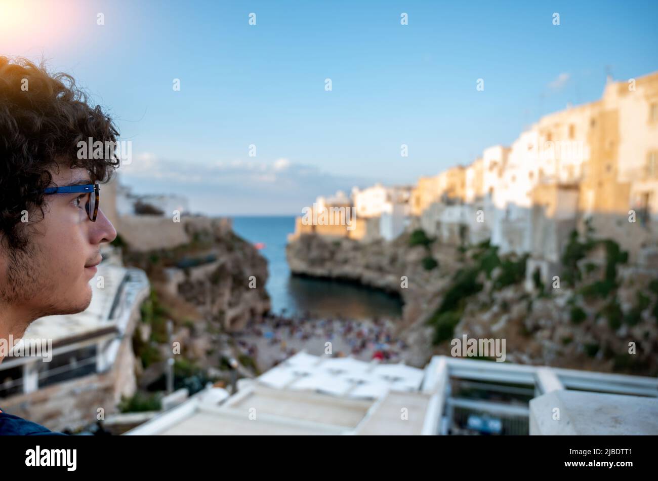 Polignano a mare, Puglia, Italy. August 2021. A young man with curly ...