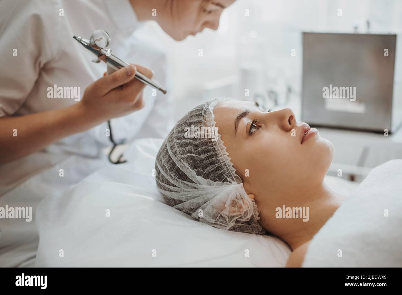 Caucasian woman receiving face oxygen peeling at cosmetology center ...