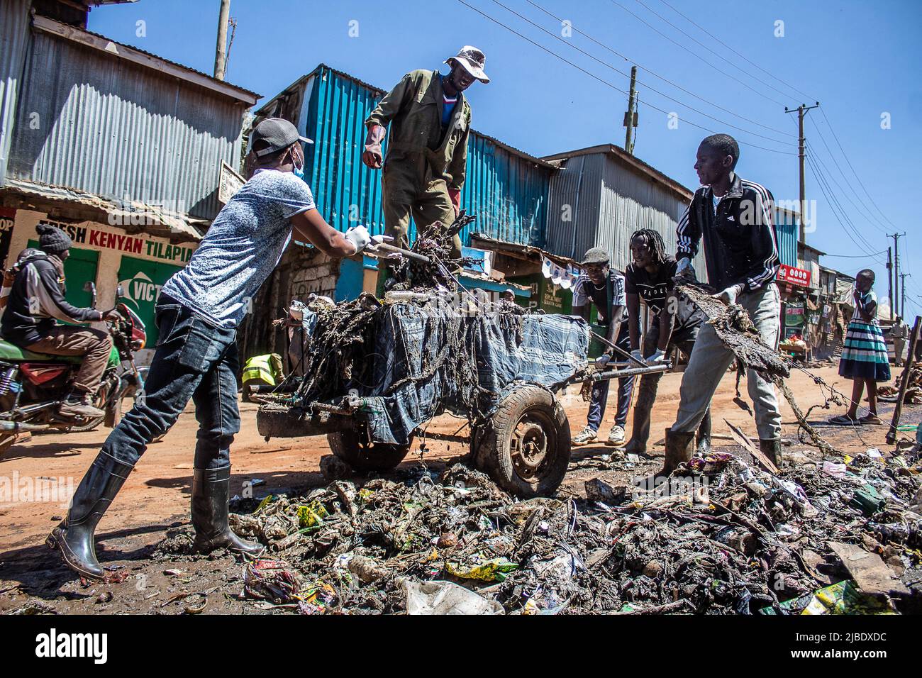 Members of a slum going green and clean taking out debris from a side ...