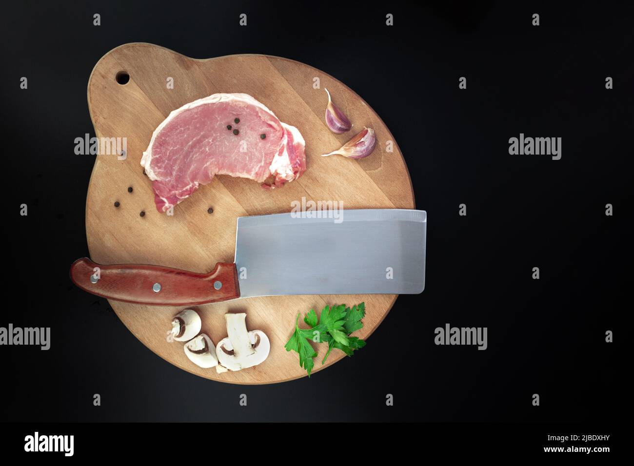 Raw meat steaks with meat knife on kitchen cutting board on dark ...