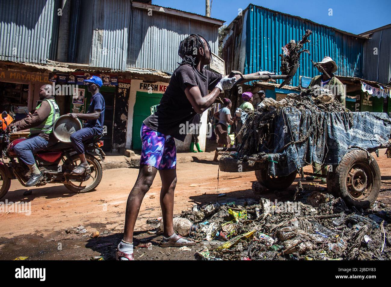 Members of a slum going green and clean taking out debris from a side ...