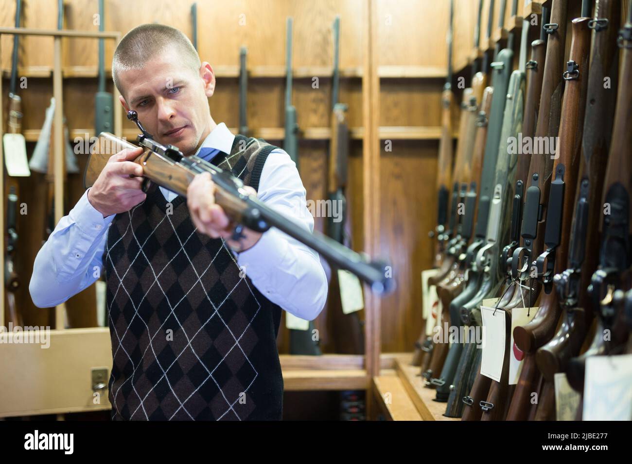 Portrait of customer which is choosing combat rifle gun in army market ...