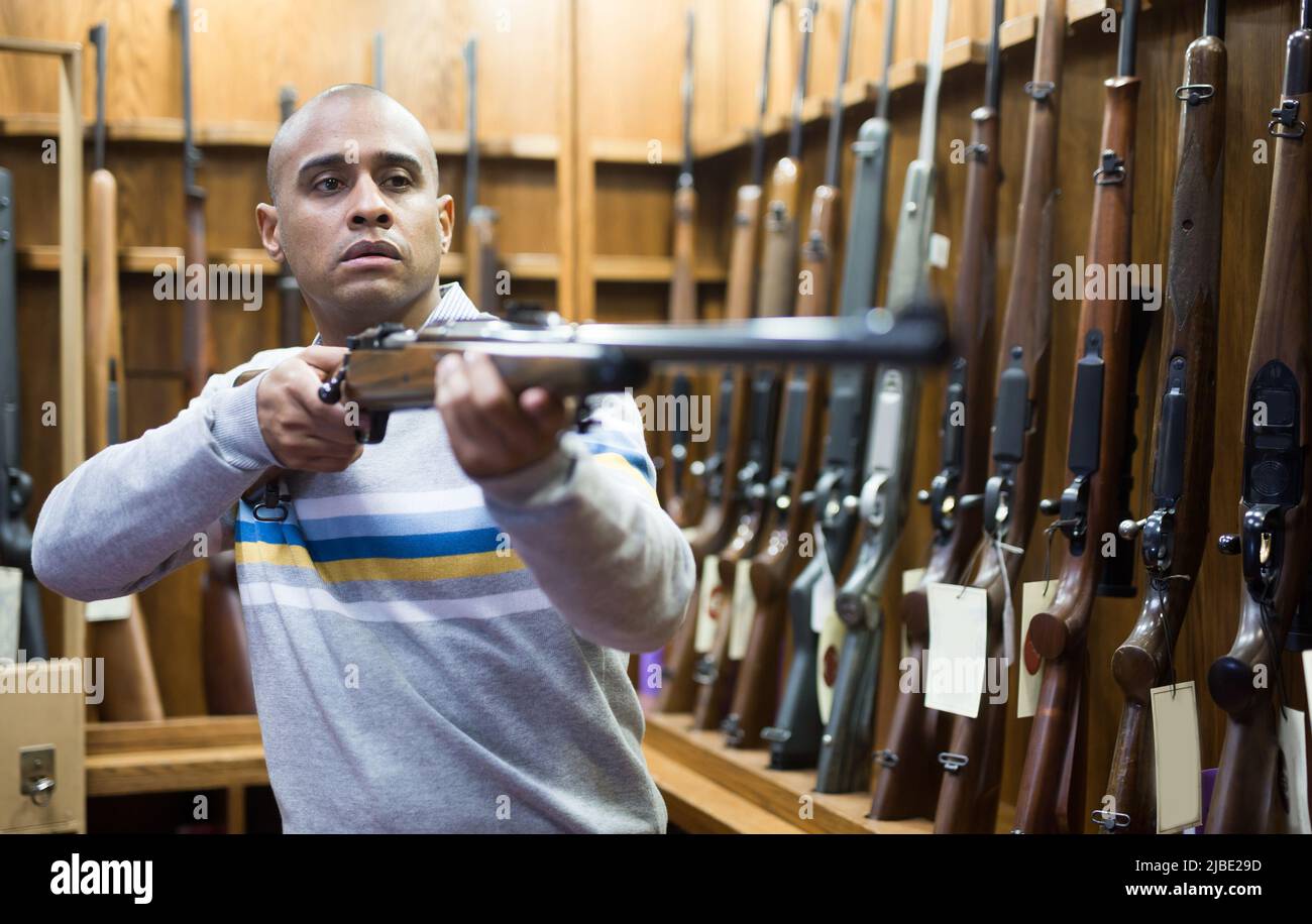 Latin american man aiming with hunting shotgun in armory shop Stock ...