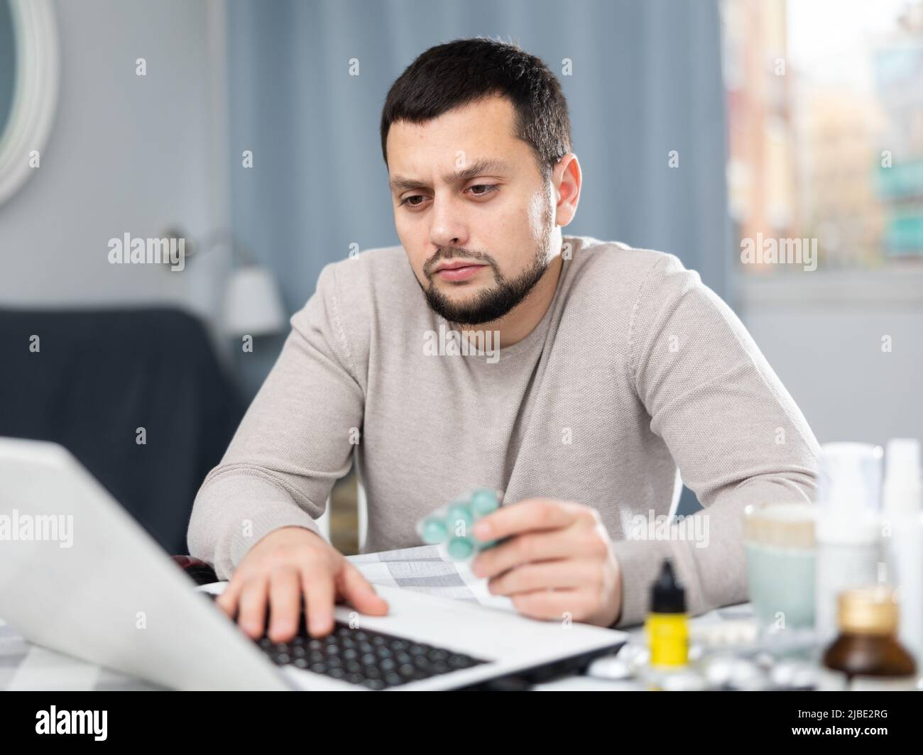 Man with pills in his hands is looking for diagnosis on the Internet ...
