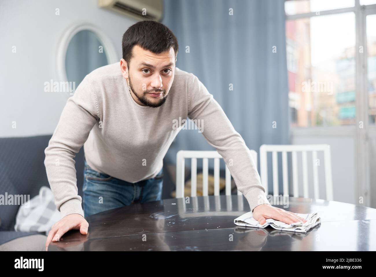 Bearded man wiping table with rag in room Stock Photo - Alamy