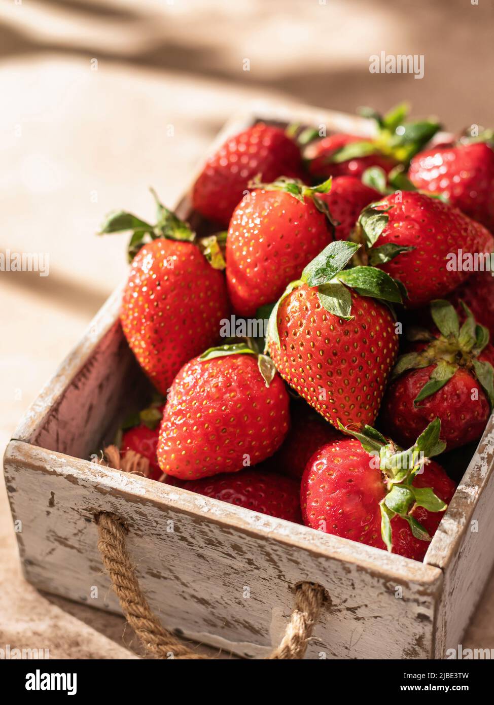 Strawberries in white rustic box on brown textured background with ...