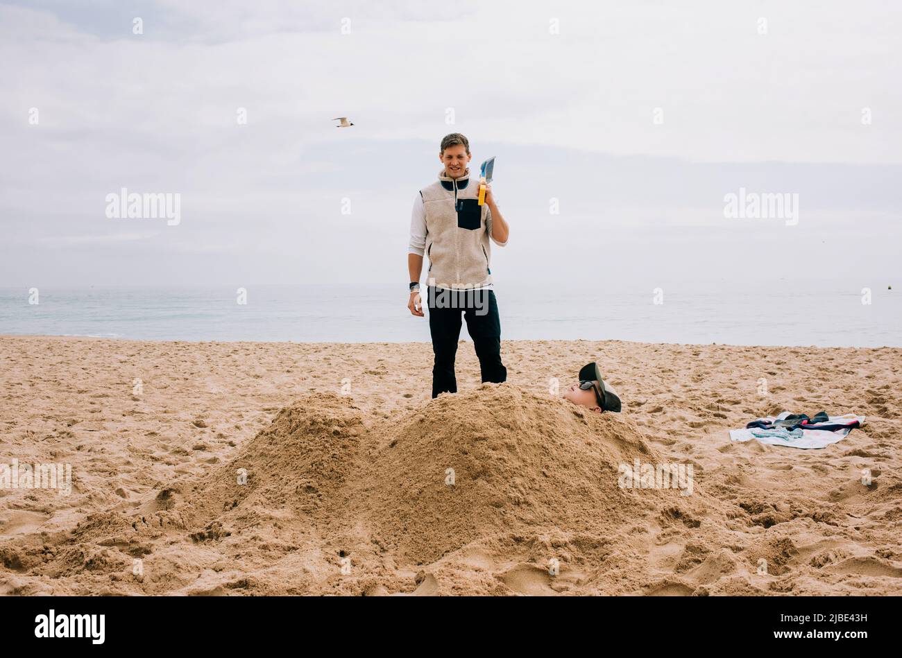 father proudly stood with spade burying his son in the sand Stock Photo ...