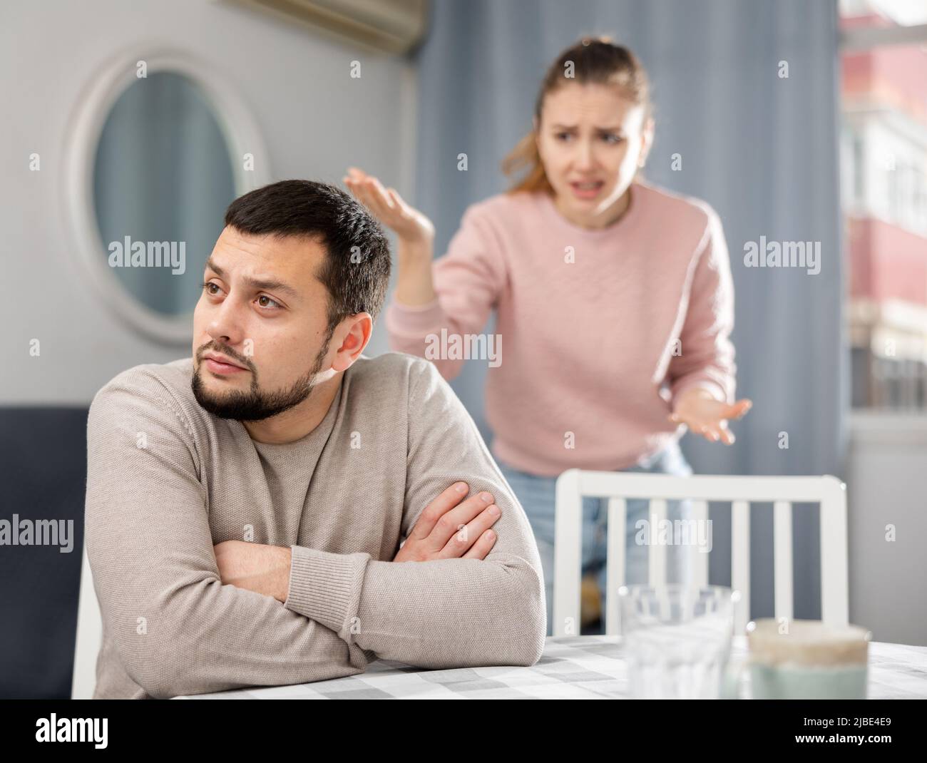 Man sitting at table during quarrel with his wife Stock Photo - Alamy