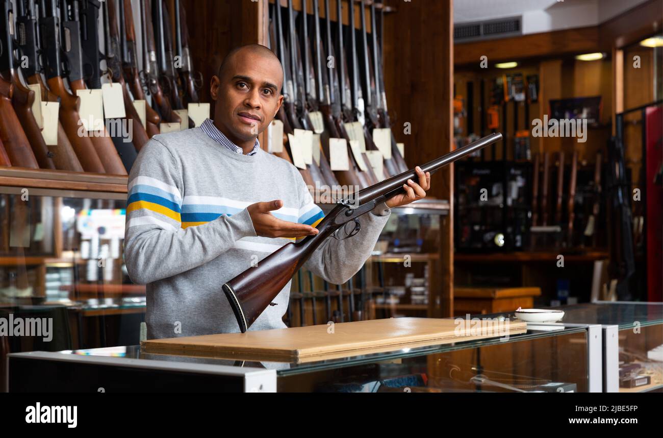 Latin american man owner of armory shop offering vintage hunting rifle ...
