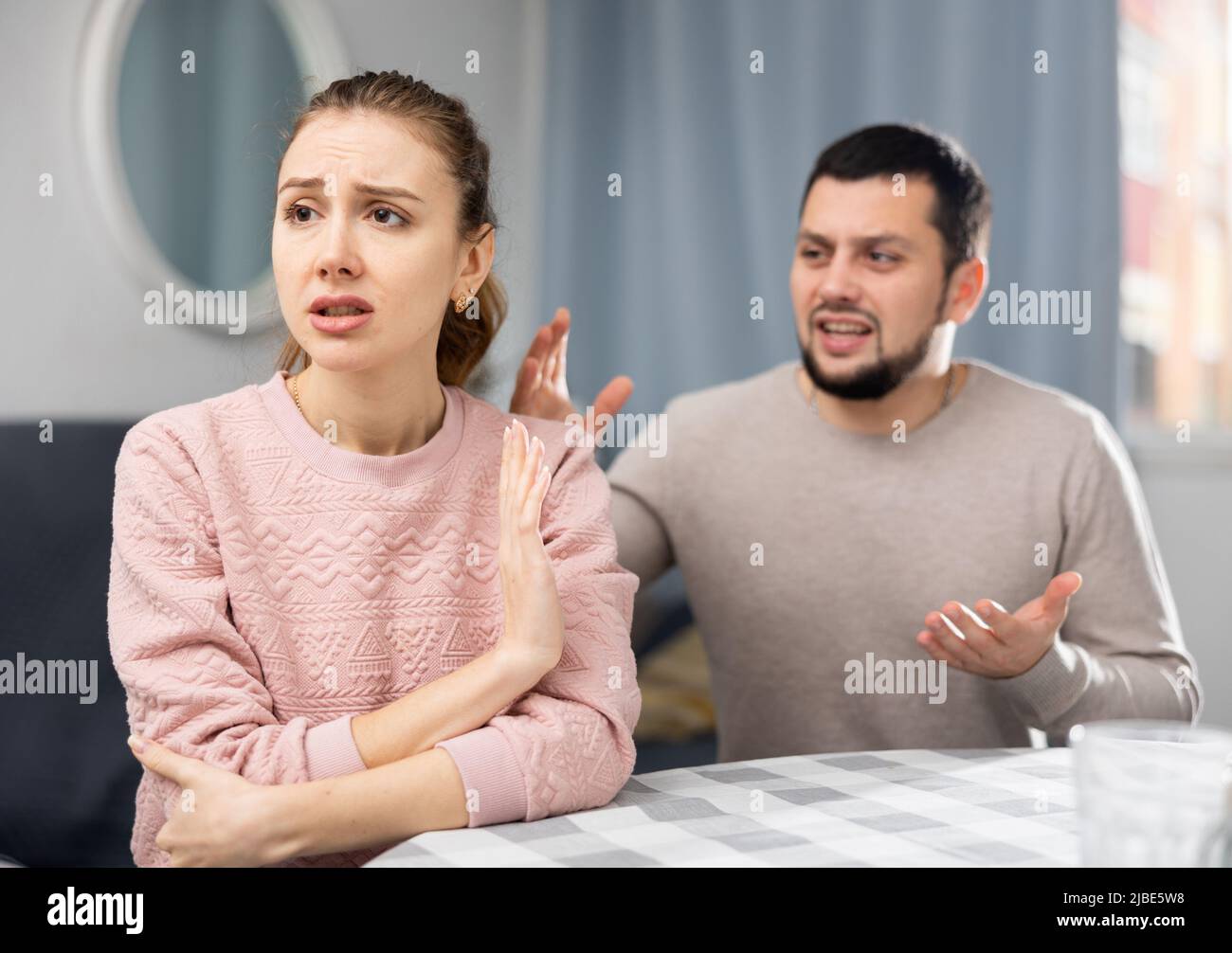 Wife and husband sitting at table at home and quarreling Stock Photo ...