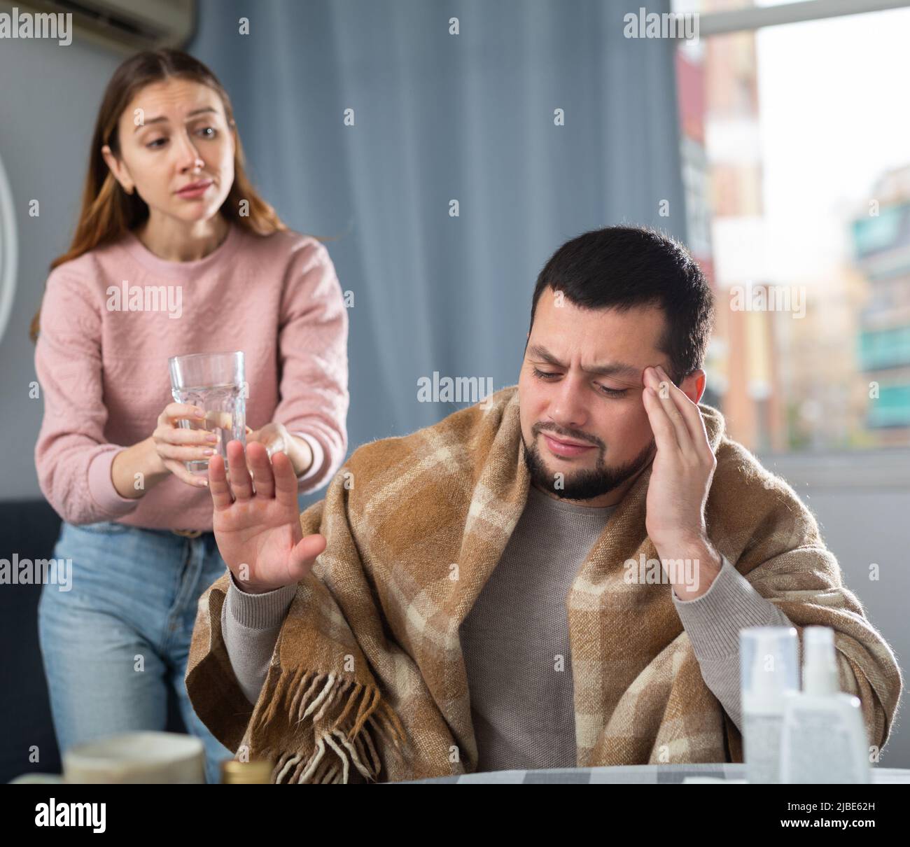 Young man with headache refusing help from caring wife Stock Photo - Alamy