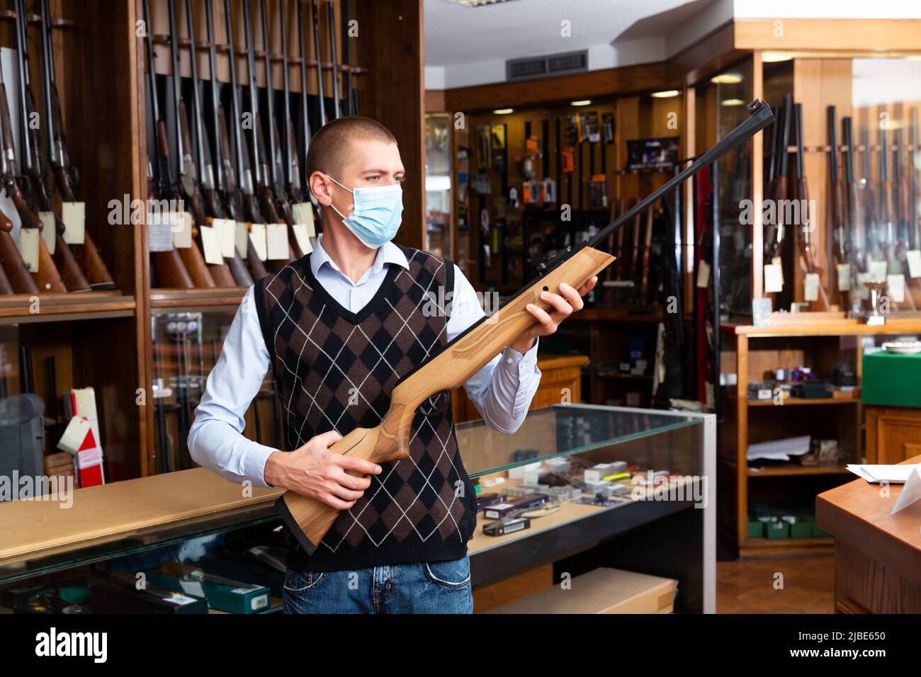 Gun shop salesman in protective mask with air rifle Stock Photo - Alamy