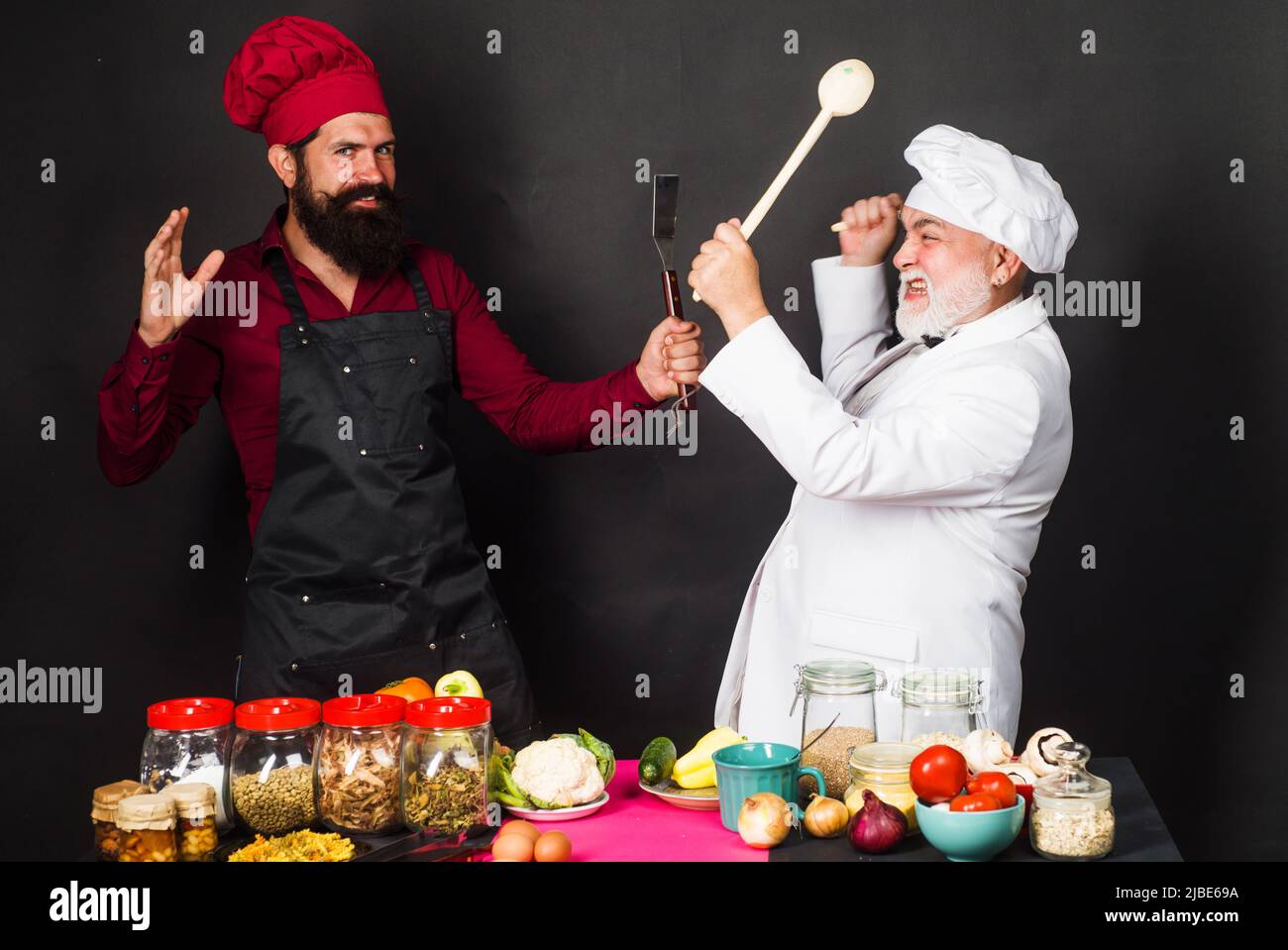 Culinary battle. Two male chefs in uniform fighting in kitchen ...