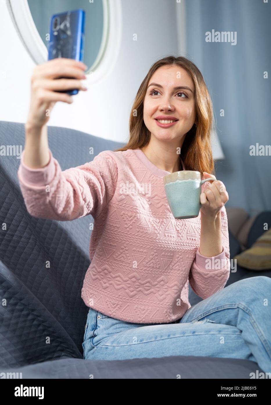 Young woman taking selfie while sitting on sofa with mug of tea Stock ...