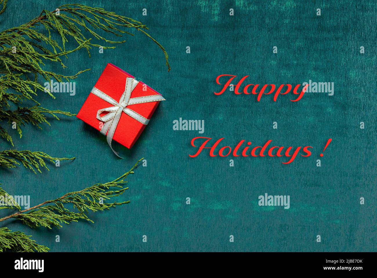 Red gift box, natural coniferous branches and Happy Holidays greeting ...