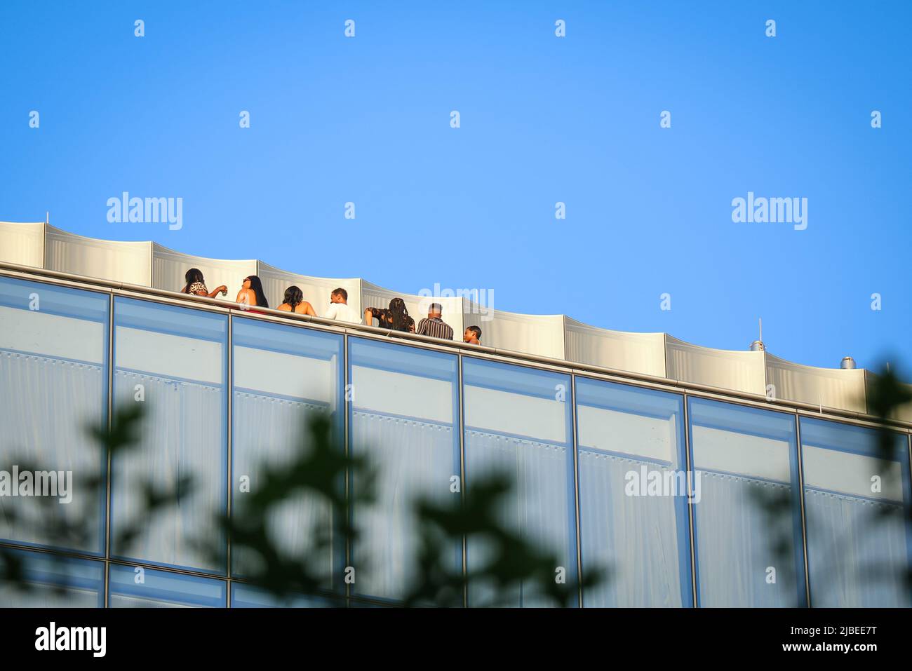 A group of people gathered and enjoying a late afternoon on a rooftop ...