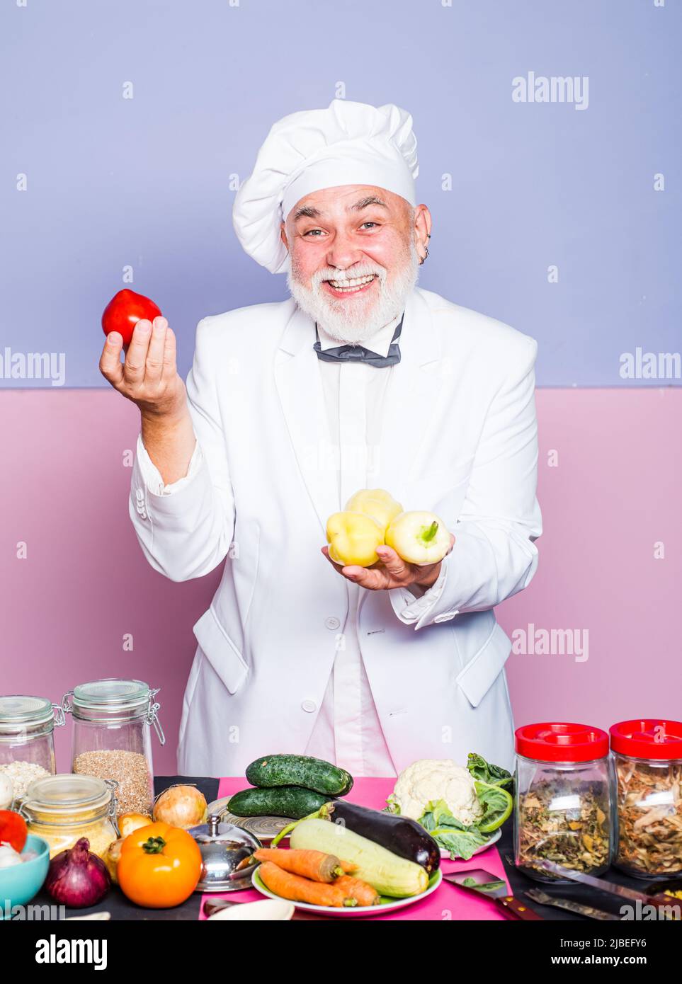 Smiling chef with blackboard and vegetables. Chef garnishing food in ...