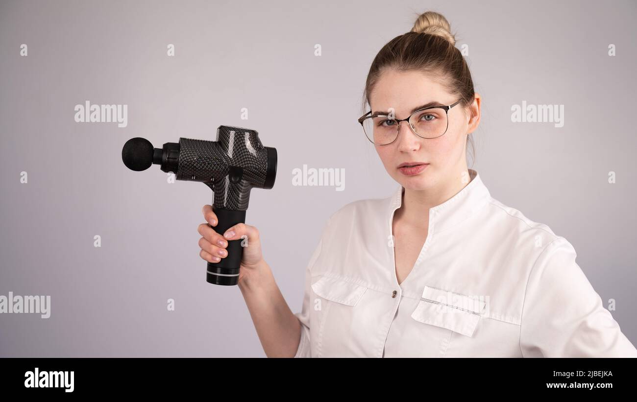 The masseur doctor holds a masseur gun on a white background Stock ...