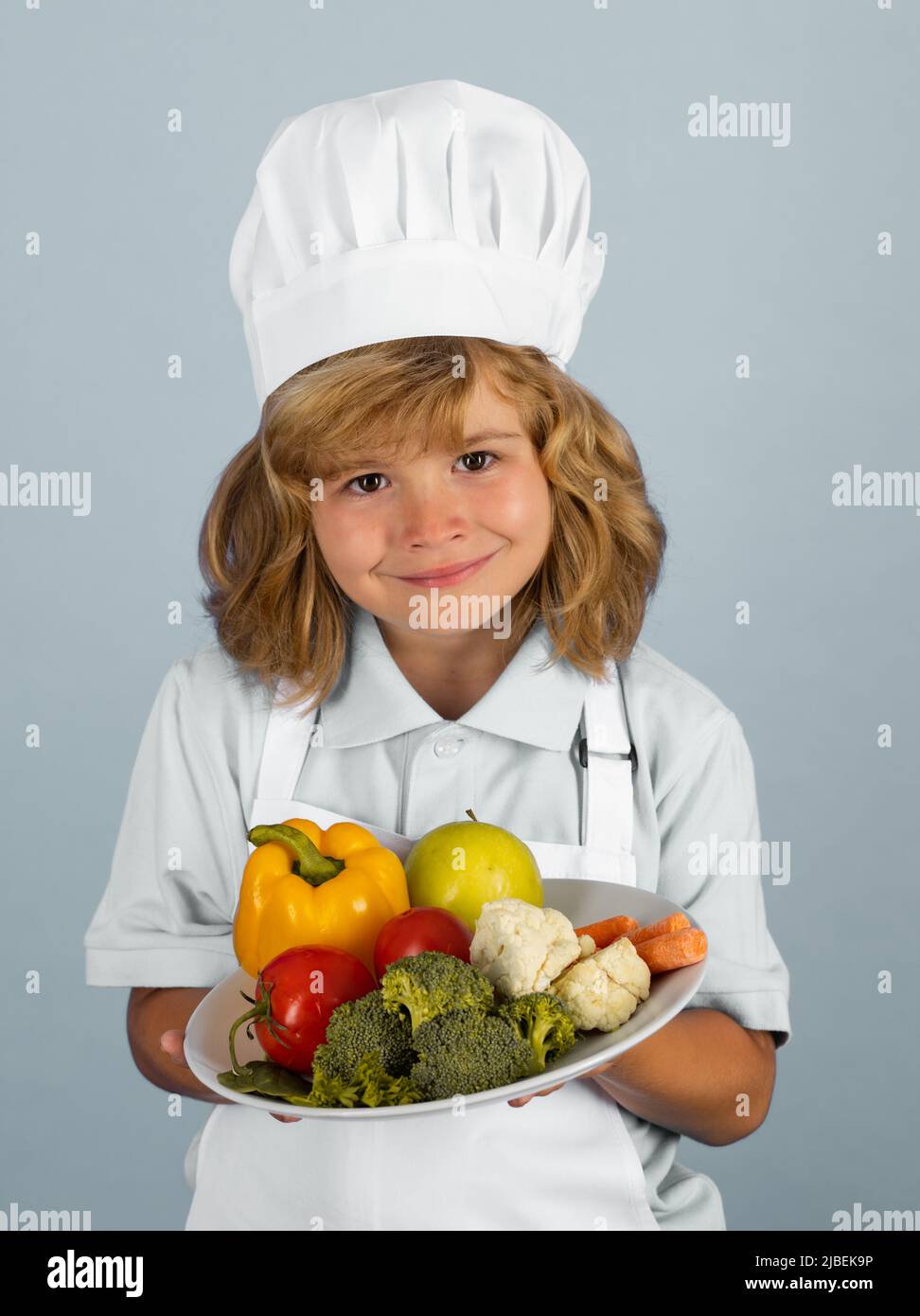 Child chef cook hold plate with vegetables prepares food on isolated ...