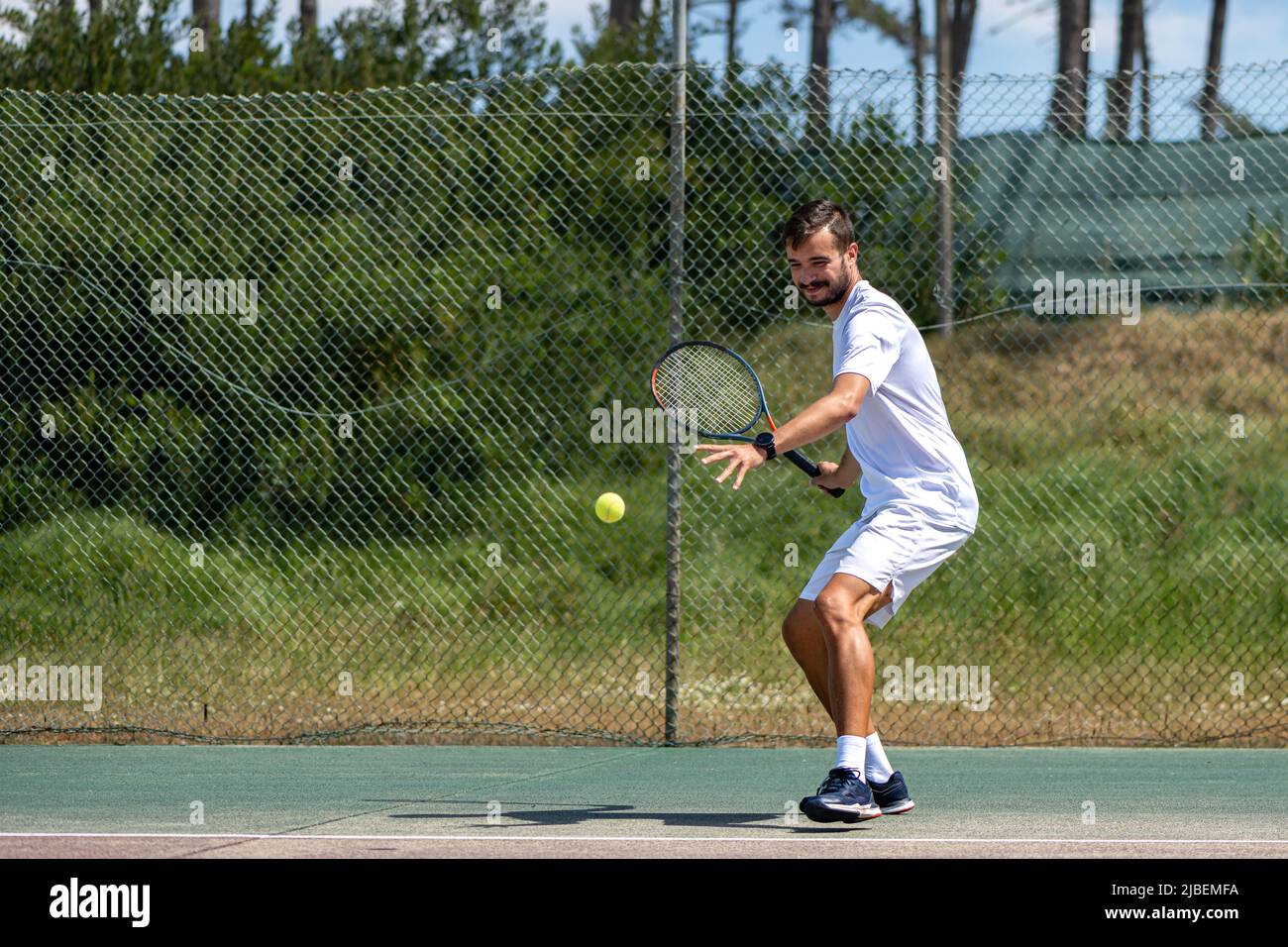 Tennis player hitting forehand at ball with racket on court Stock Photo ...