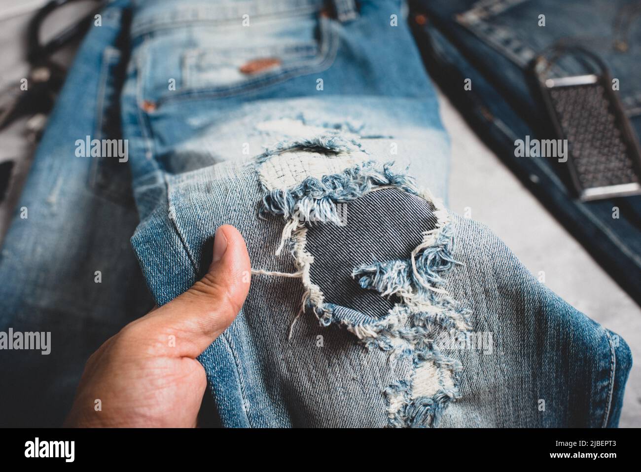 The man making ditressed jeans. DIY ripped jeans with scissors and ...