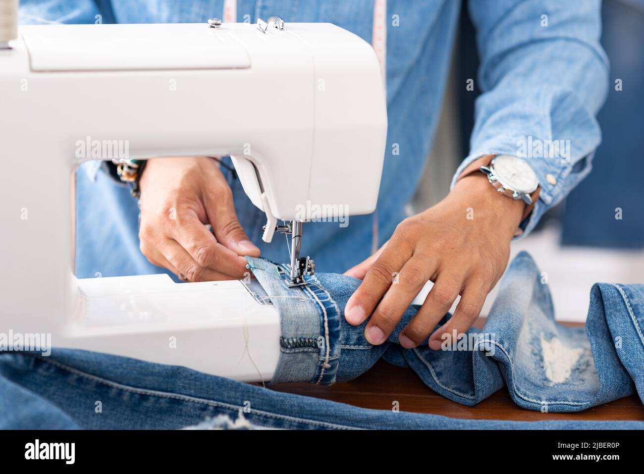 Tailor working with blue denim jeans. Tailor hem the blue jeans Stock ...