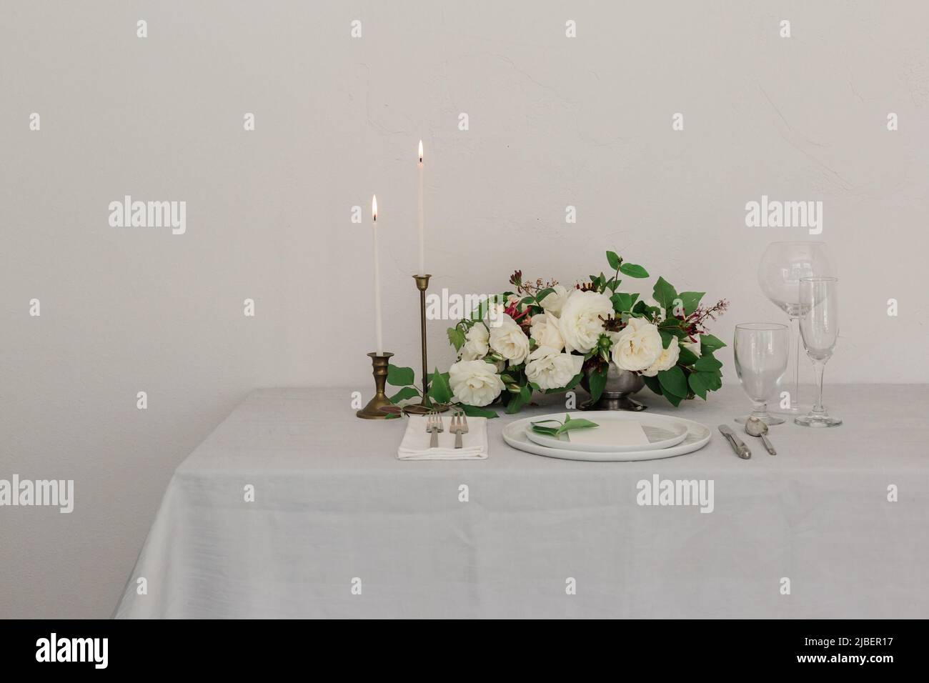 A beautiful white rose floral arrangement on a dinner table with ...