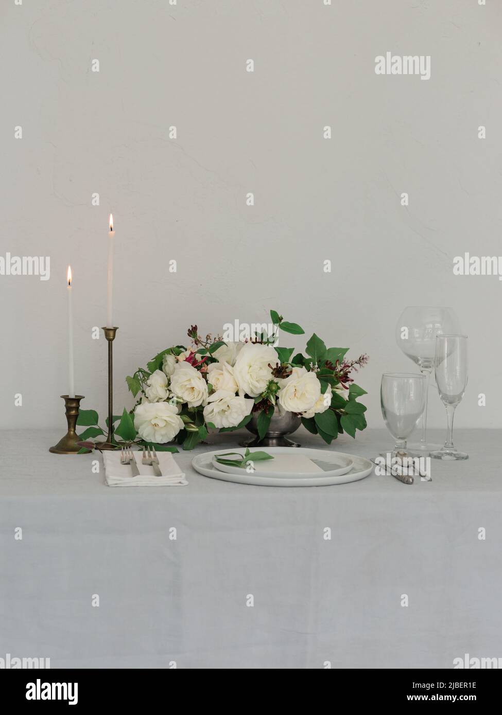 A beautiful white rose floral arrangement on a dinner table with ...