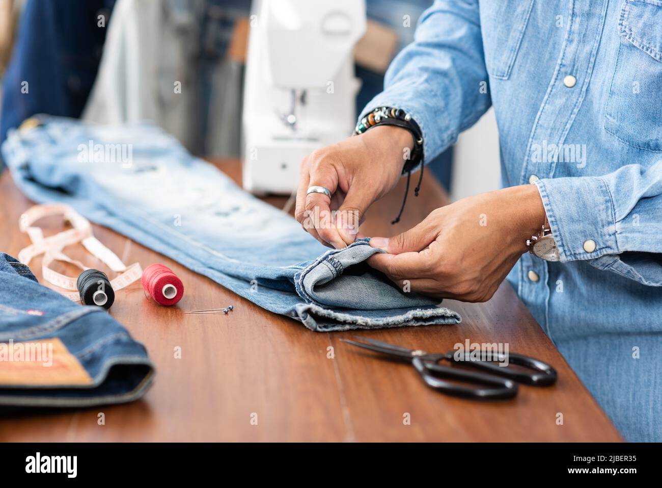 Tailor working with blue denim jeans. Tailor hem the blue jeans Stock ...