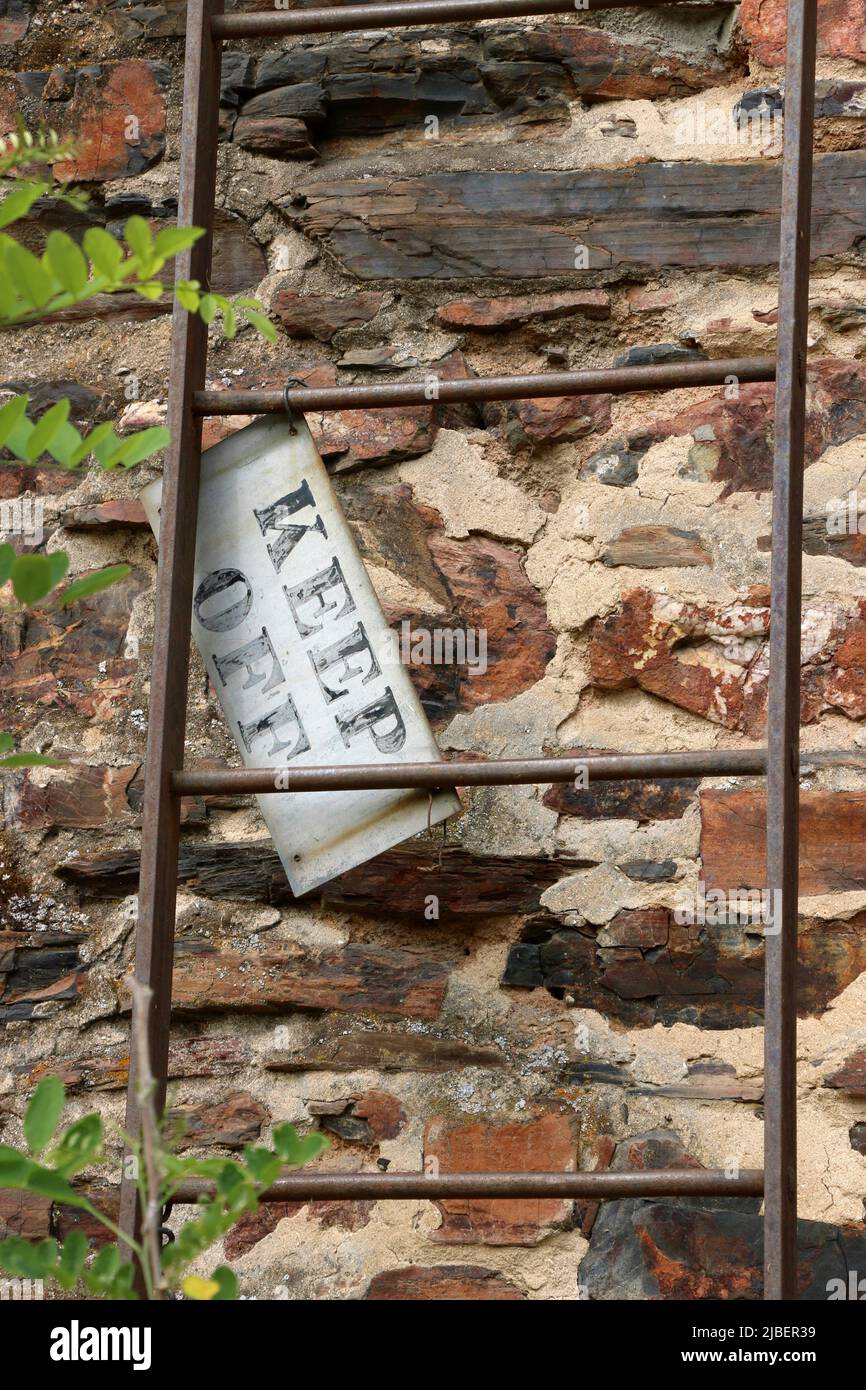 Keep Off sign hangs on a rusted ladder leaning against an abandoned ...