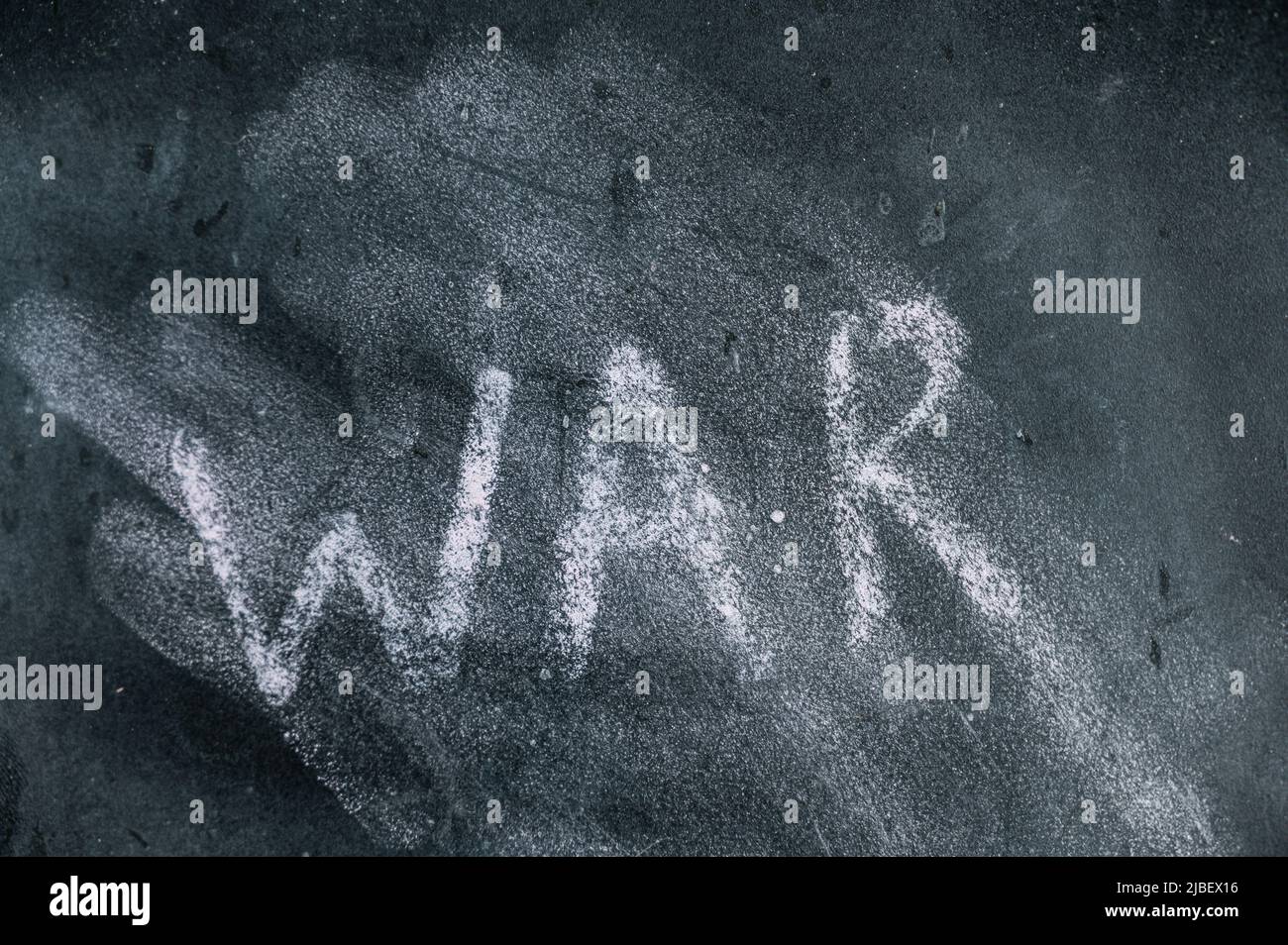 Semi-erased word WAR on black chalkboard. Handwritten word. Fuzzy ...