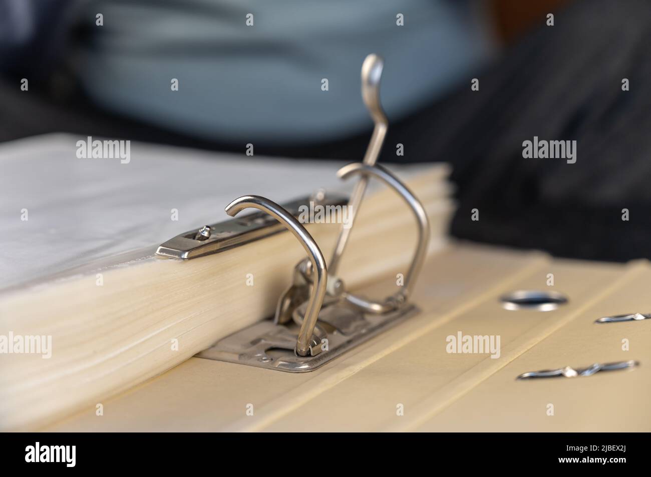 Open gray file folder with metal binder. Papers are on a black desk ...