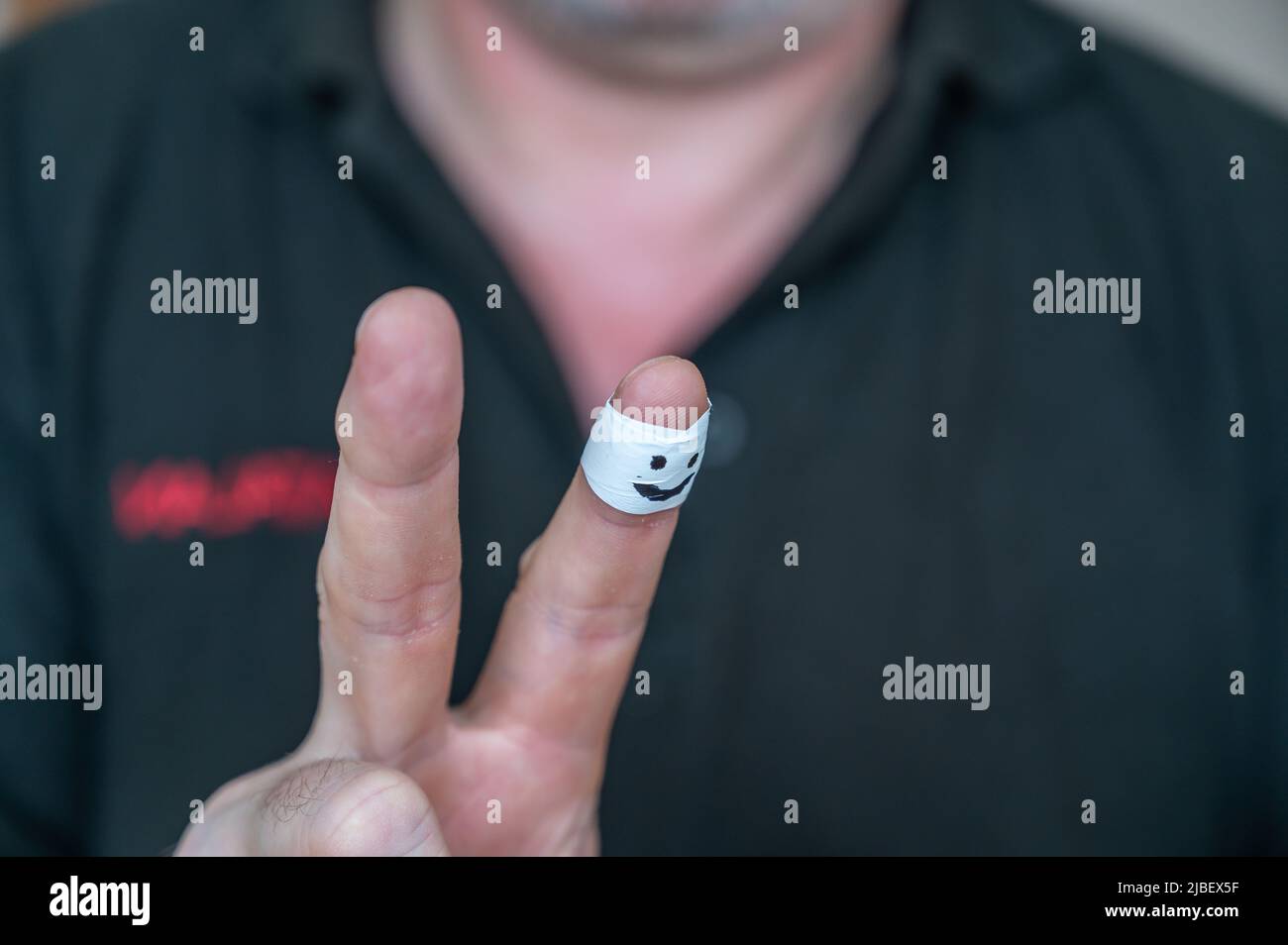 Close-up of a man's hand showing a gesture of victory. White armband on ...
