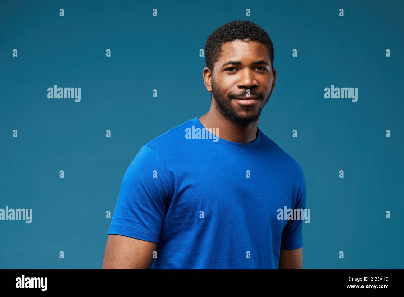 Portrait of smiling black man wearing blue shirt on vibrant blue ...