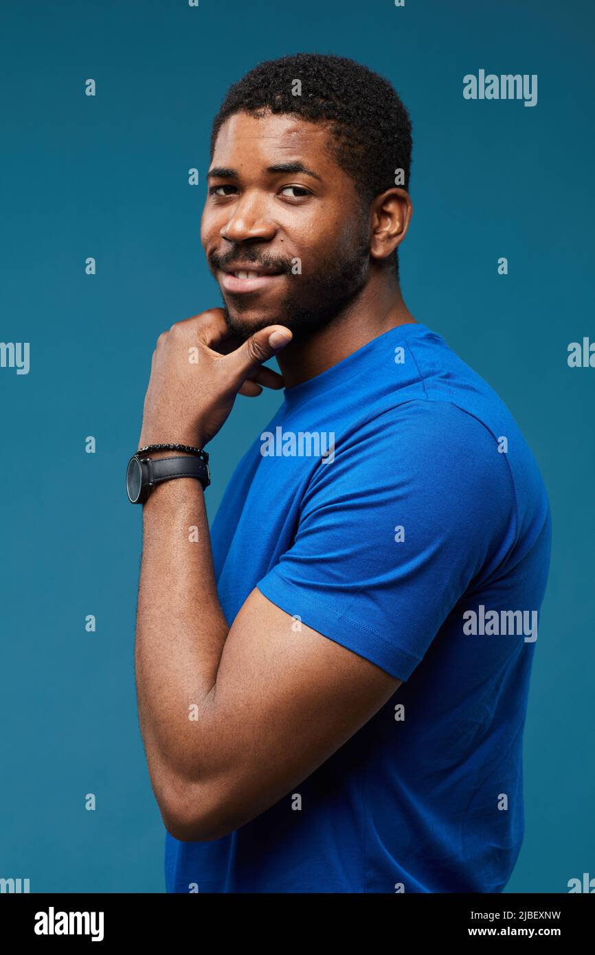 Vertical portrait of handsome black man looking at camera over shoulder with smug expression and ...