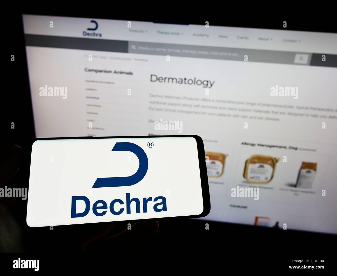 Person holding smartphone with logo of British company Dechra ...