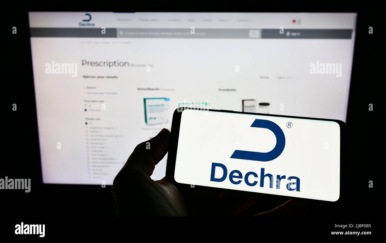 Person holding mobile phone with logo of British company Dechra ...