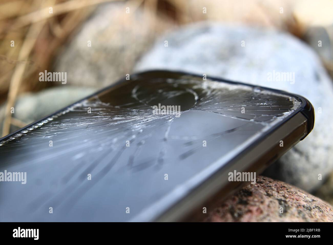 Mobile phone with broken display lying on rocks Stock Photo - Alamy