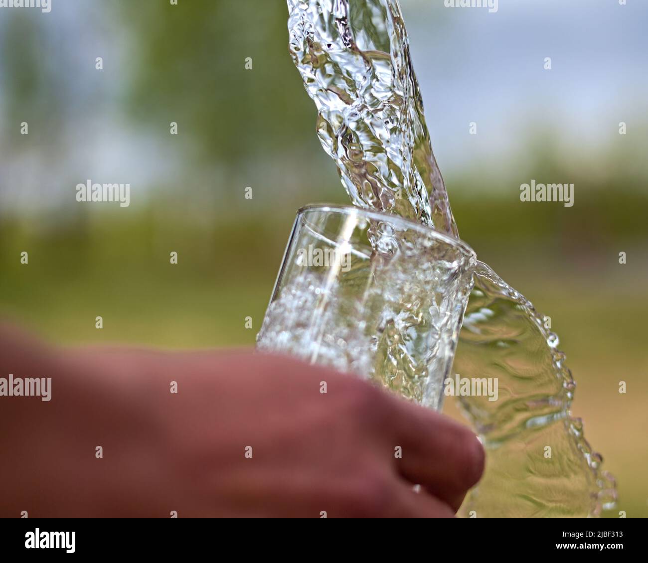 Water is poured in a glass and flows over Stock Photo - Alamy