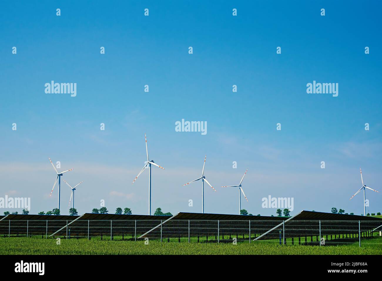 Windmill turbine generator and solar battery panels against blue sky ...