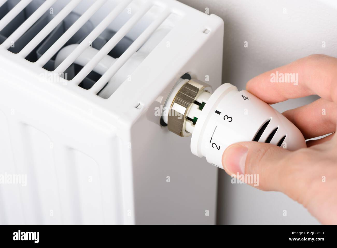 Hand adjusting the valve knob of heating radiator temperature ...