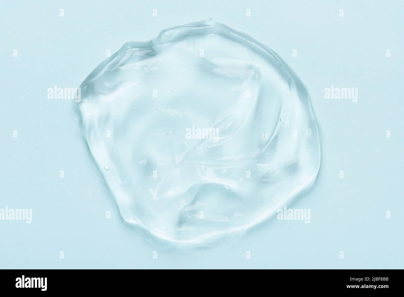 Clear cosmetic skincare gel with bubbles on blue background top view ...