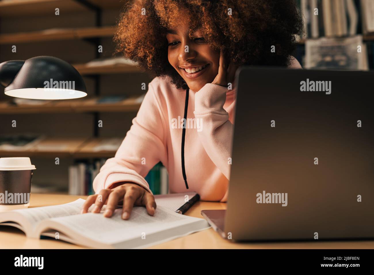 Smiling student studying late at night. Young female using book and ...