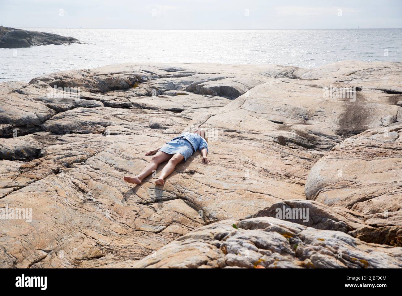 Woman sunbathing rocks beach hi-res stock photography and images - Alamy