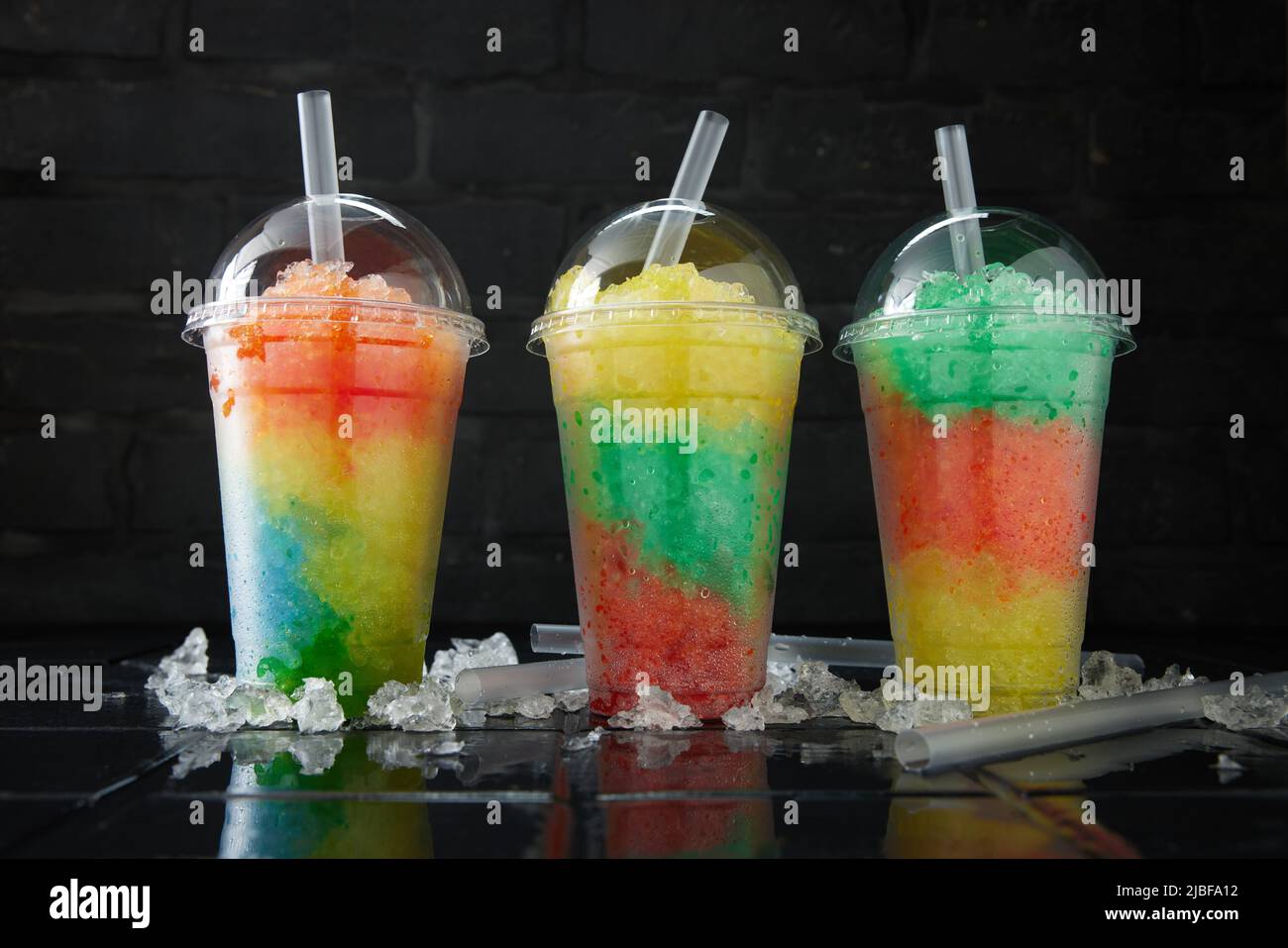 Assortment of various slush drinks in a row on black and dark ...