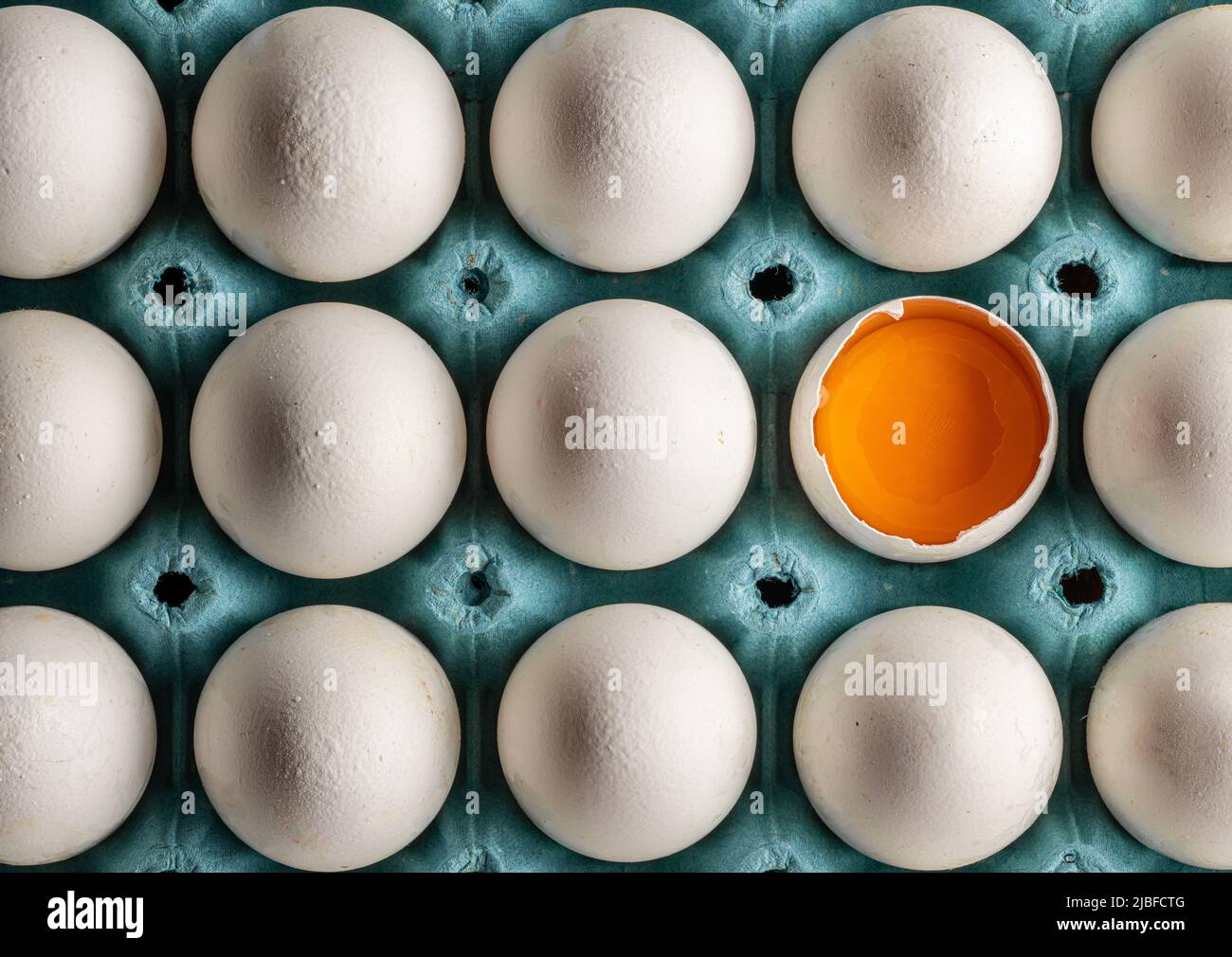 Organic fresh chicken eggs arranged in egg tray. half broken egg with ...
